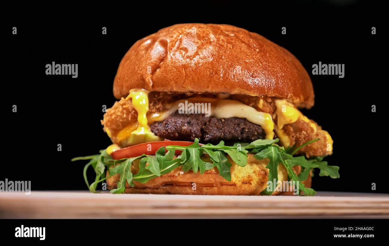 Craft burger is cooking on black background in black food gloves ...