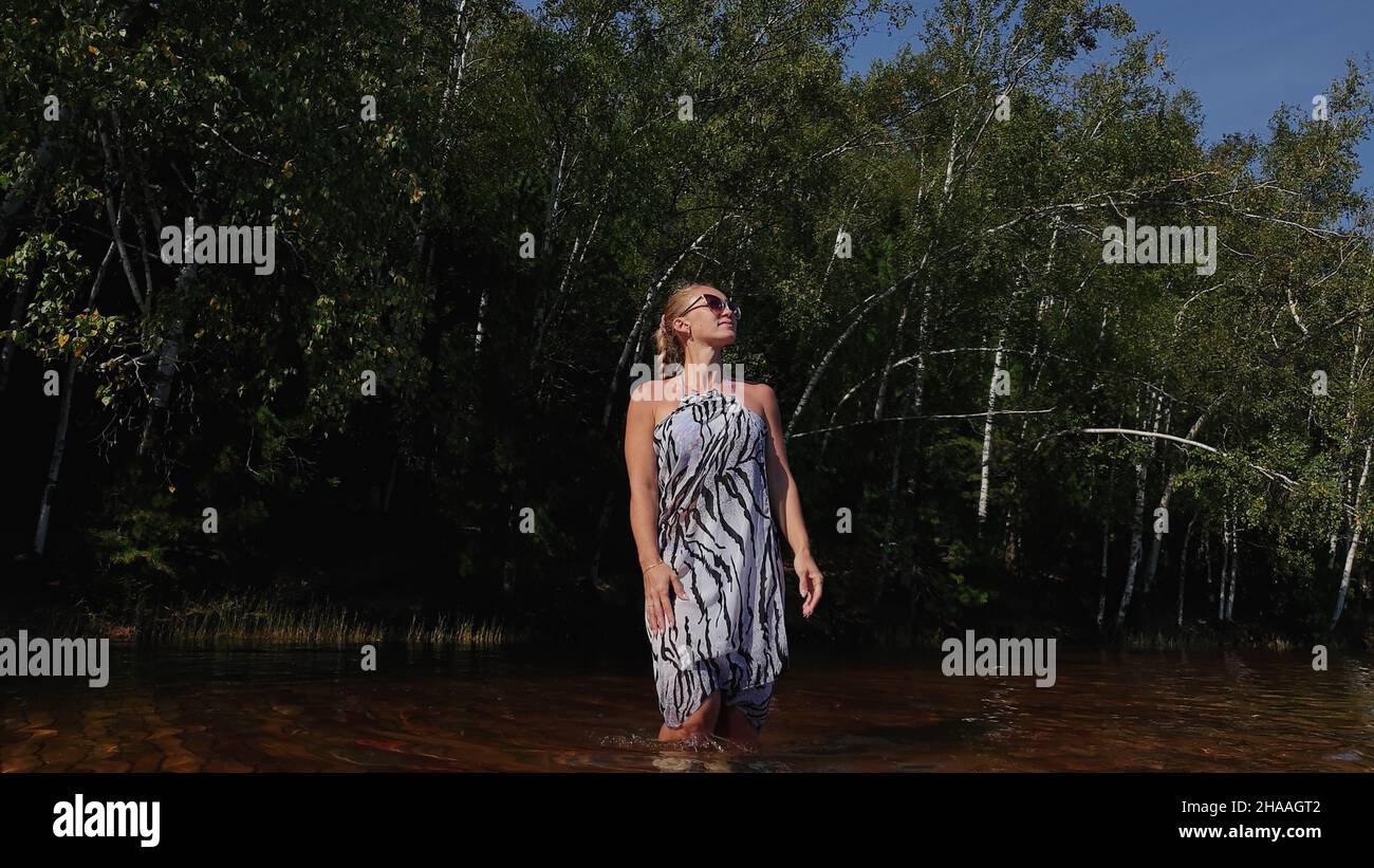 Woman walk on water on pier in sunglasses and a boho silk shawl. Girl ...