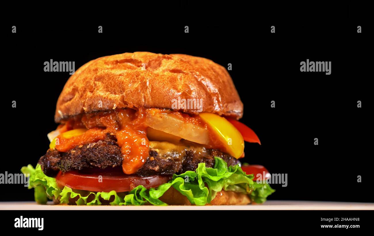 Craft burger is cooking on black background in black food gloves ...