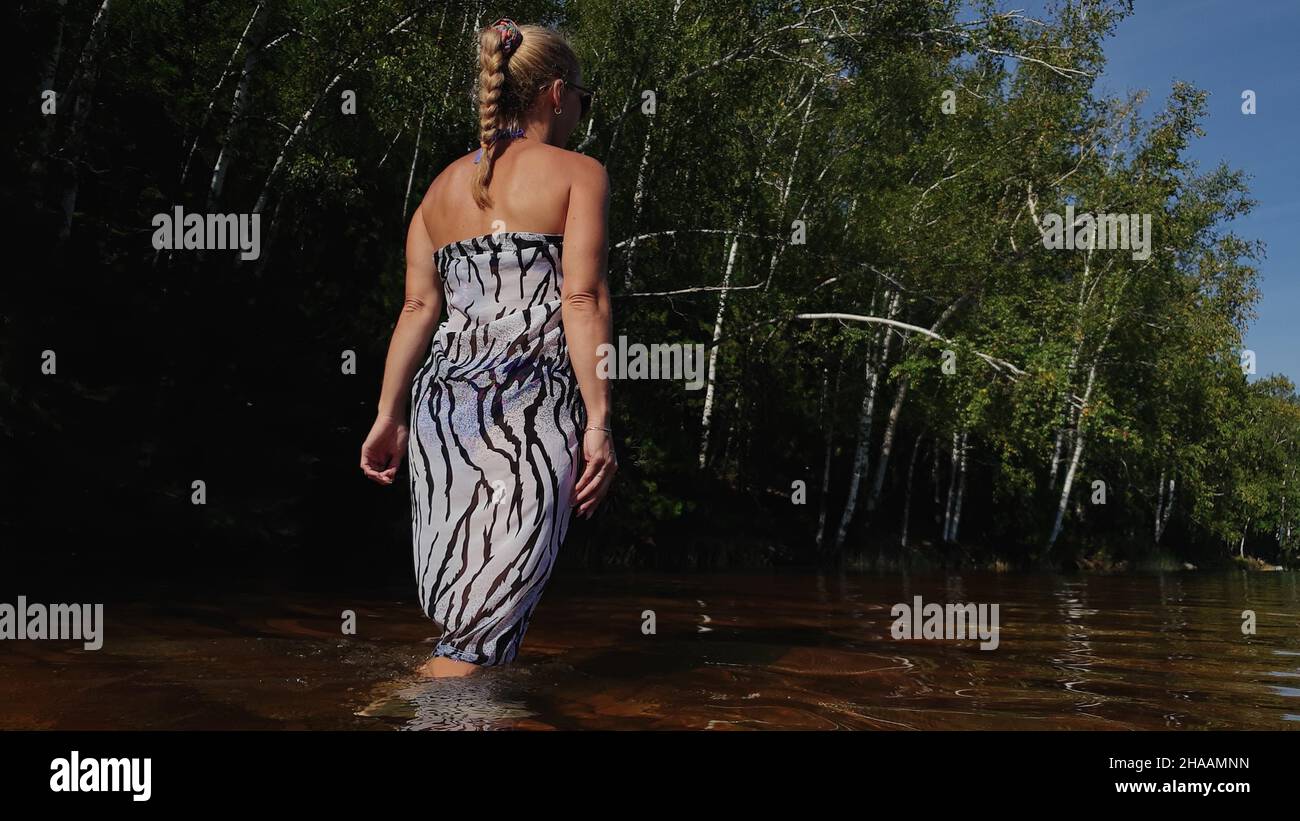 Woman walk on water on pier in sunglasses and a boho silk shawl. Girl ...
