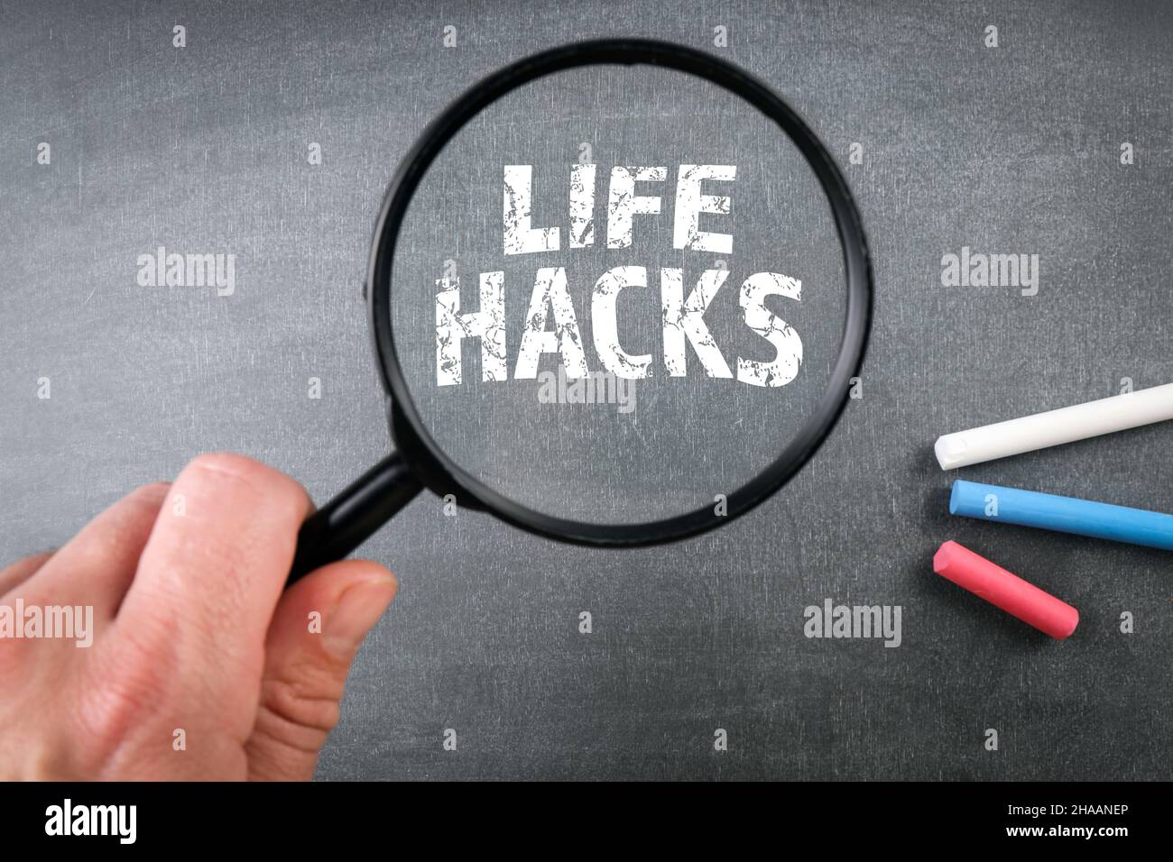 Life Hacks concept. Colored pieces of chalk and a magnifying glass on a ...