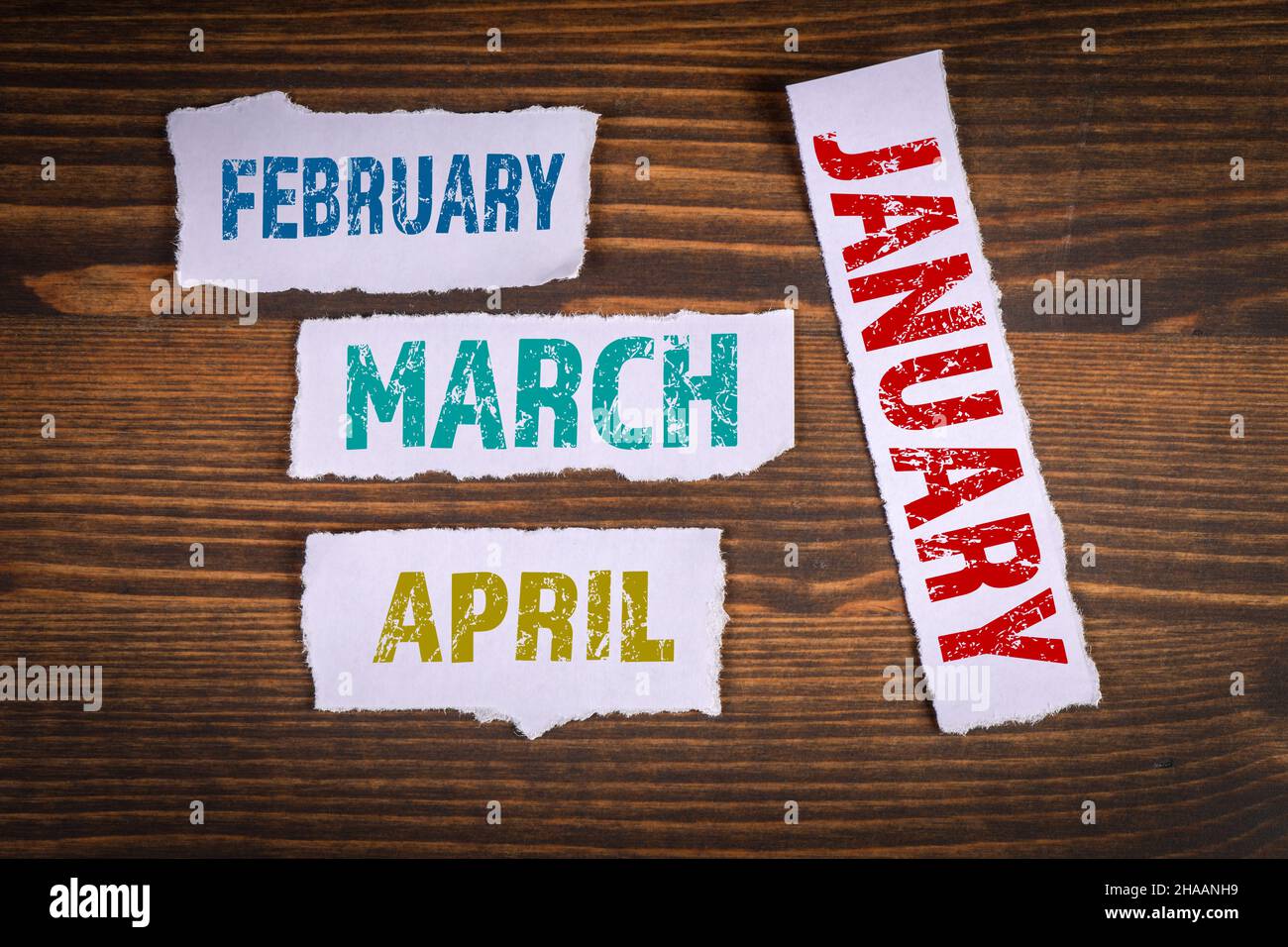 January February March and April. Torn paper on a wooden background ...