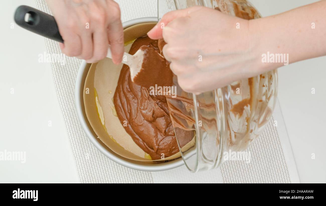 Chocolate cake recipe. Pouring cake batter into a baking pan. Close up ...