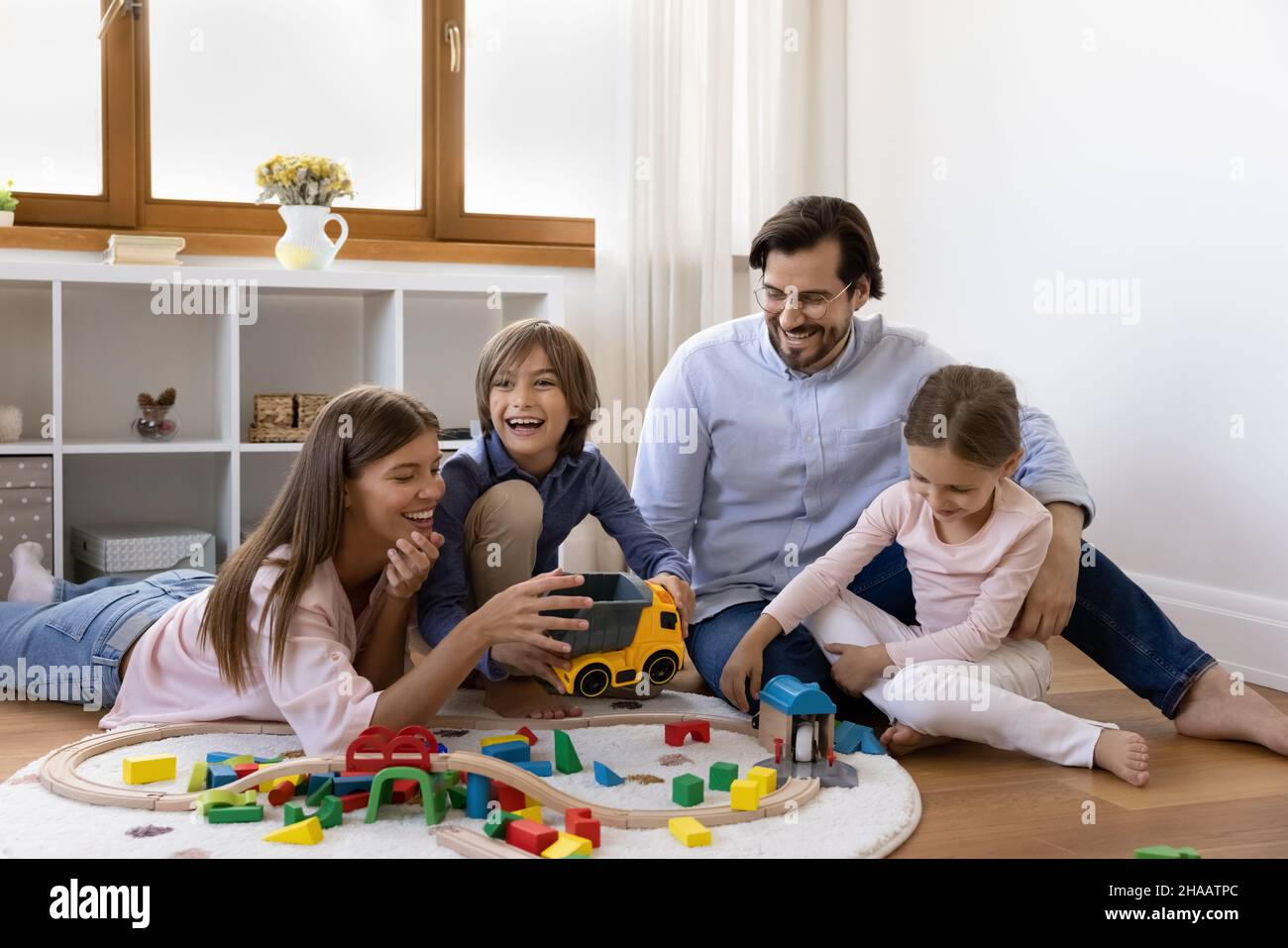 Happy parents and little children playing games on warm floor Stock ...