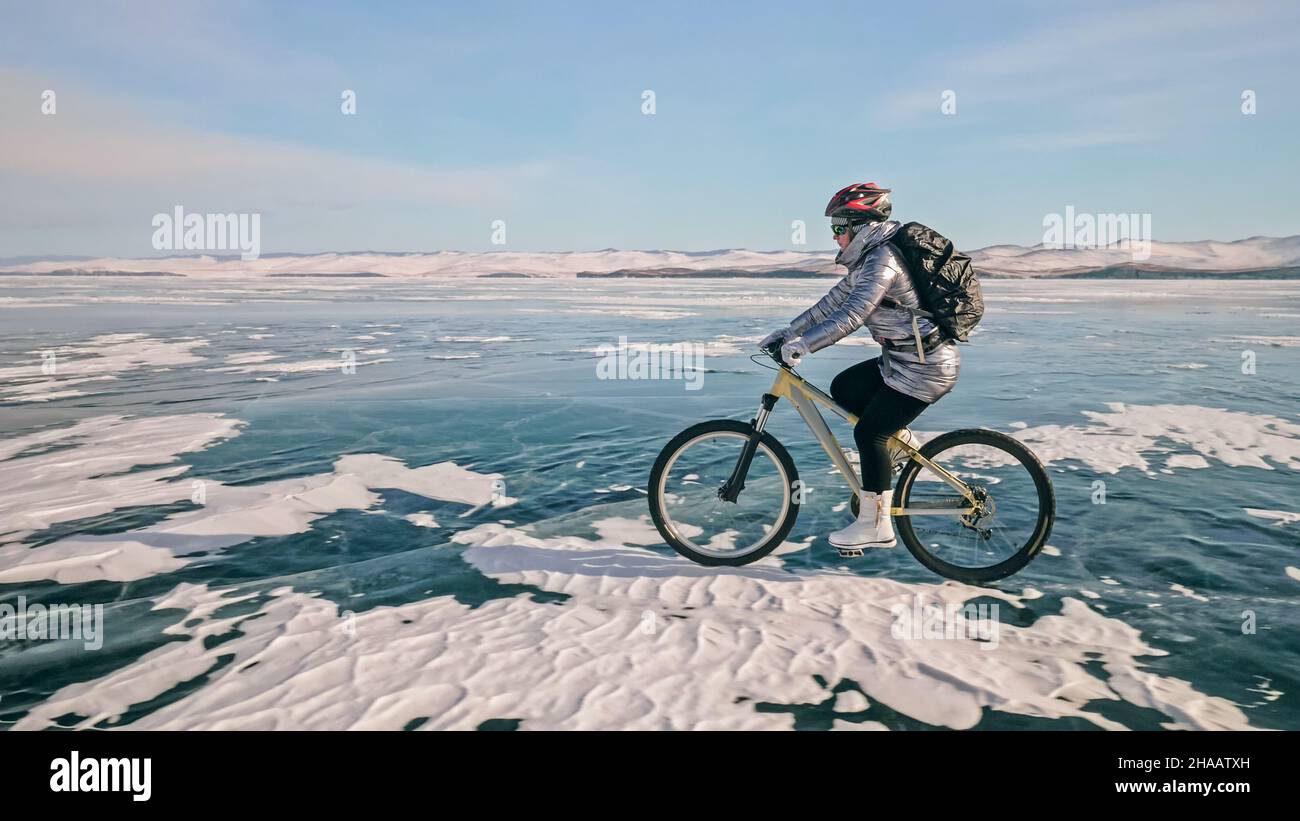 Woman is riding bicycle on the ice. Tires on bike are covered wi Stock ...