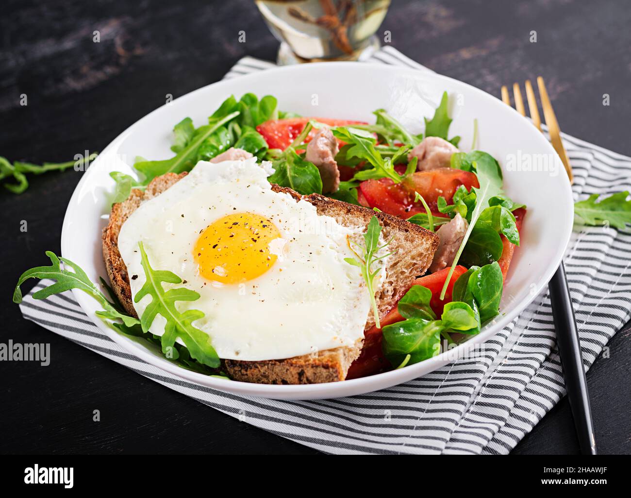 Breakfast - toast with fried eggs and tomatoes salad with greens and ...