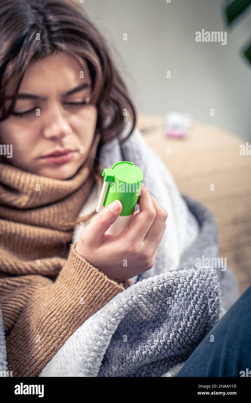 A sick young woman using cough spray Stock Photo - Alamy