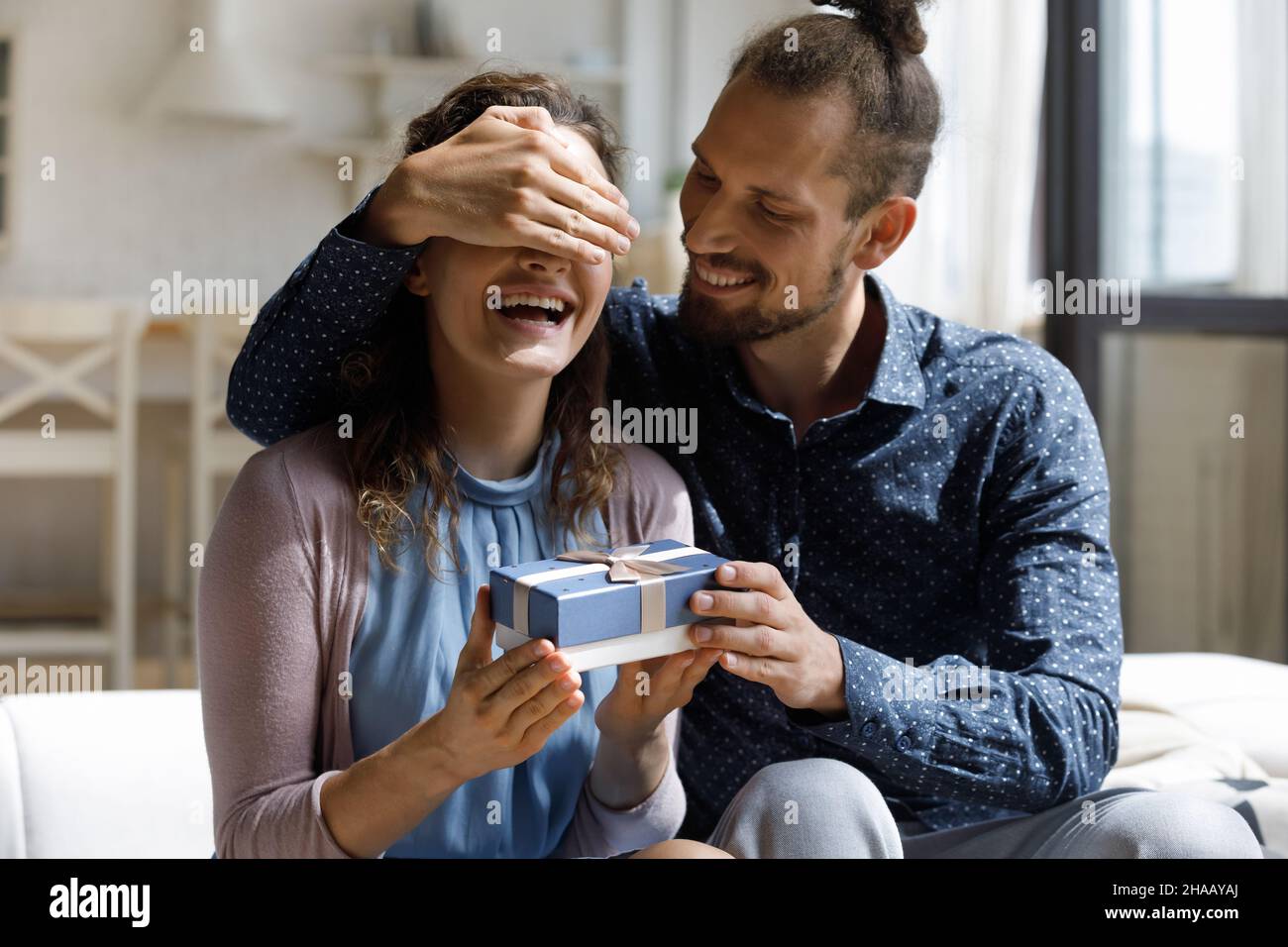 Happy laughing boyfriend giving surprise gift to excited girlfriend ...