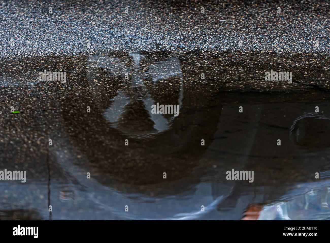 puddle on the pavement with a reflection of the car wheel, close-up ...