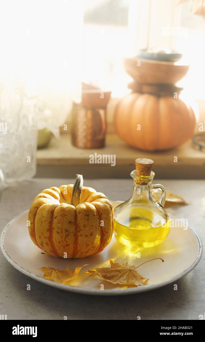 Little pumpkin, cooking oil in glass decanter and yellow autumn leaf on ...