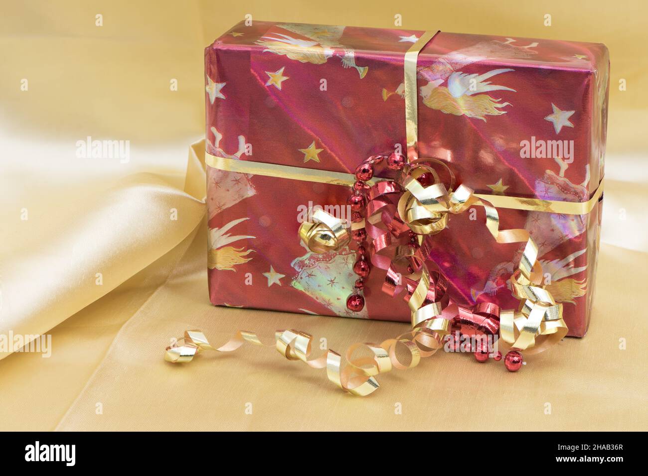 artfully wrapped gift in red and gold presented on a luxury golden ...