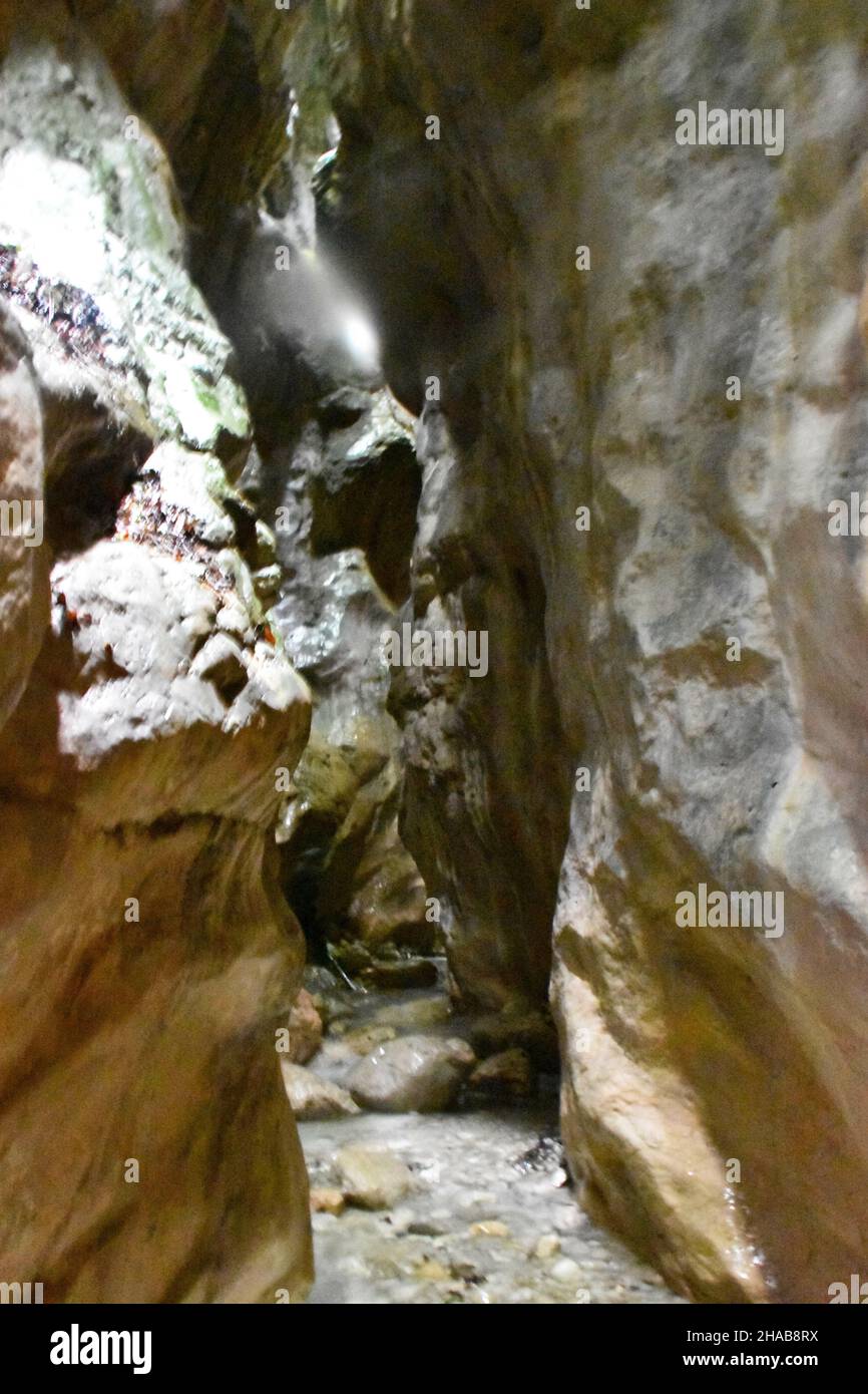 A view inside the cave with rays of light and small stones in a shallow ...