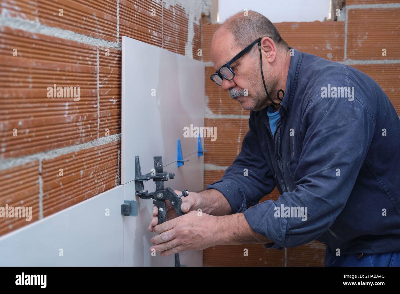 Professional tiler adjusting the separation between tiles on the wall ...
