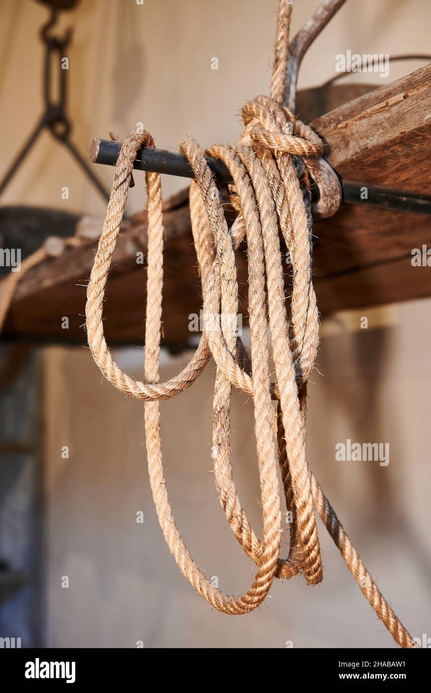 Detail of an old hemp rope hanging from an iron bar and a wooden shelf ...