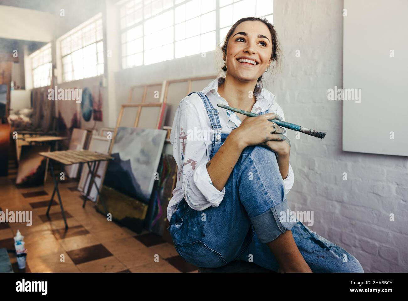 Excited female painter smiling in her art studio. Cheerful young artist ...