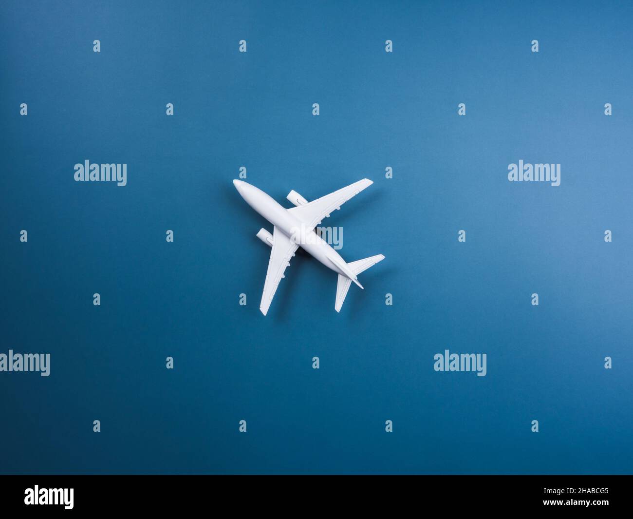 White plane toy model at the center on blue background, top view ...