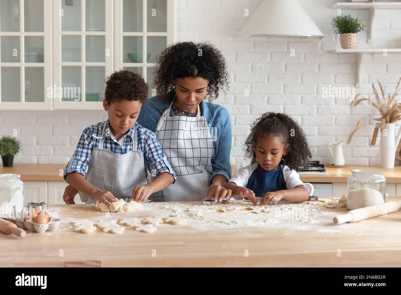 African woman teach little adorable children cooking homemade cookies ...
