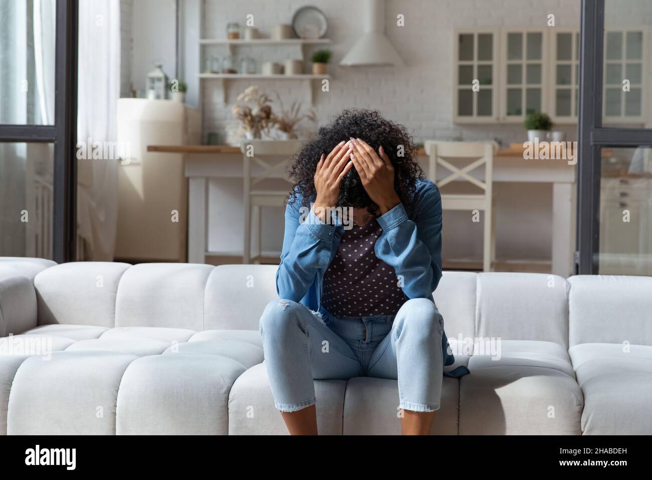 African woman sit on sofa crying feels desperate Stock Photo - Alamy