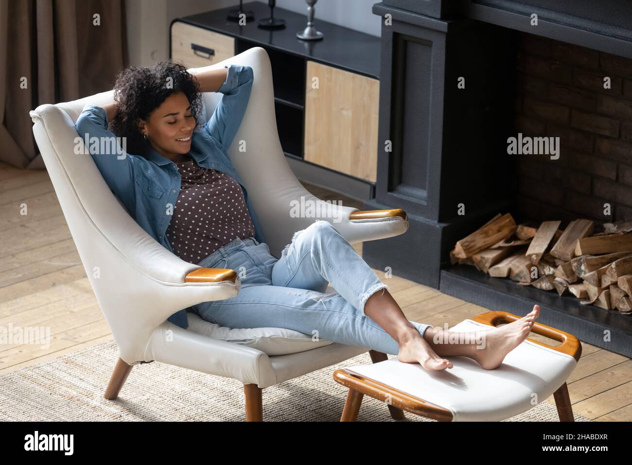 African woman put feet on footstool relaxing on cozy armchair Stock ...