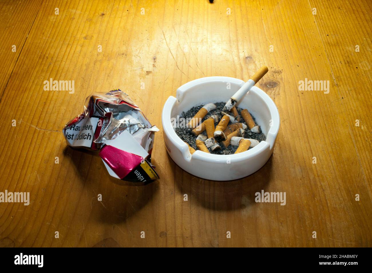 ashtray full of cigarette butts and ashes with burning cigarette and ...