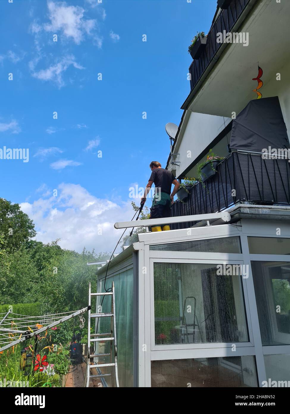 Man power washing conservatory roof and windows Stock Photo - Alamy