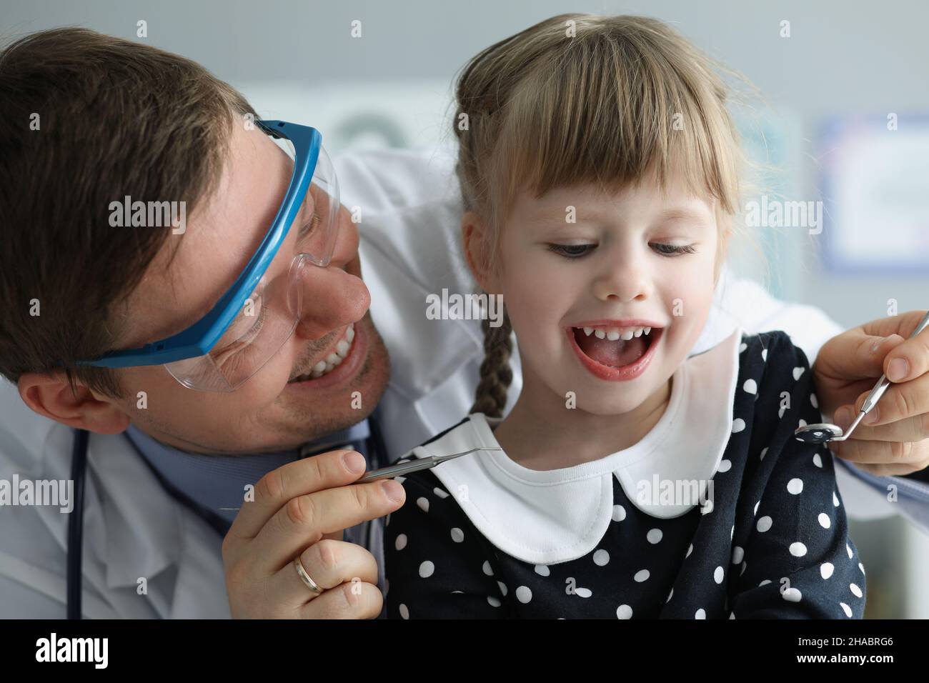 Man pediatrician check little girls health condition using special tool ...