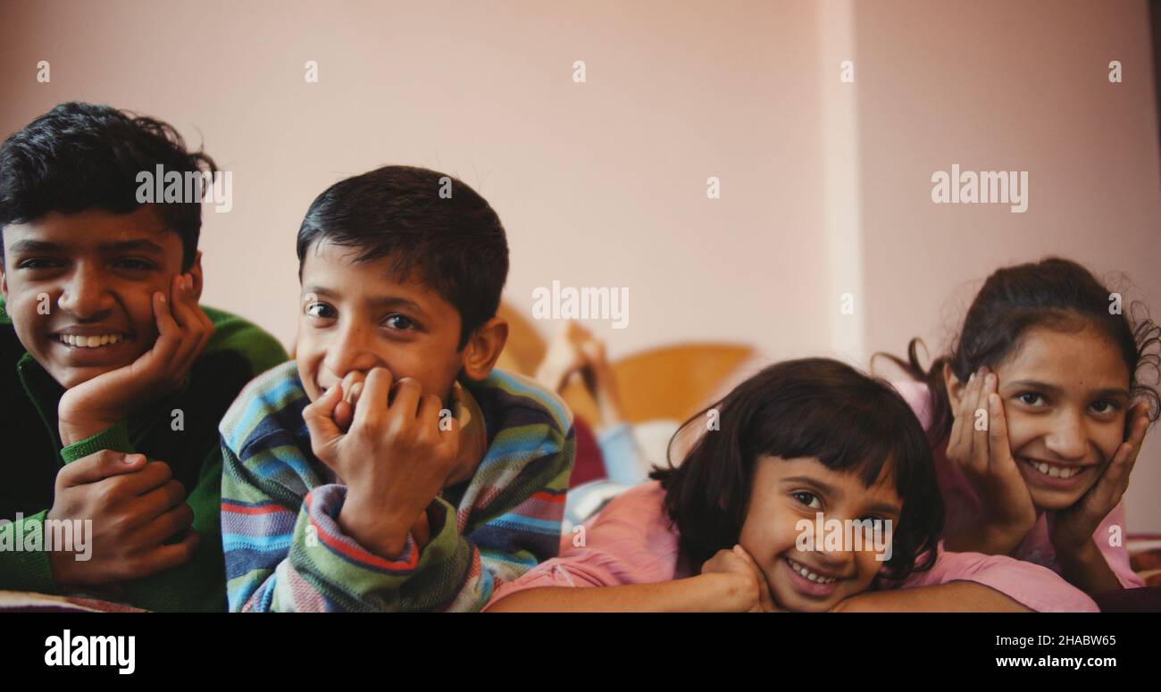 Four South Asian kids lying in the bed and smiling Stock Photo - Alamy