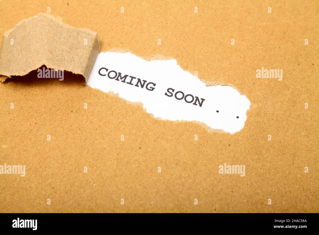 ripped brown paper revealing the words coming soon Stock Photo - Alamy