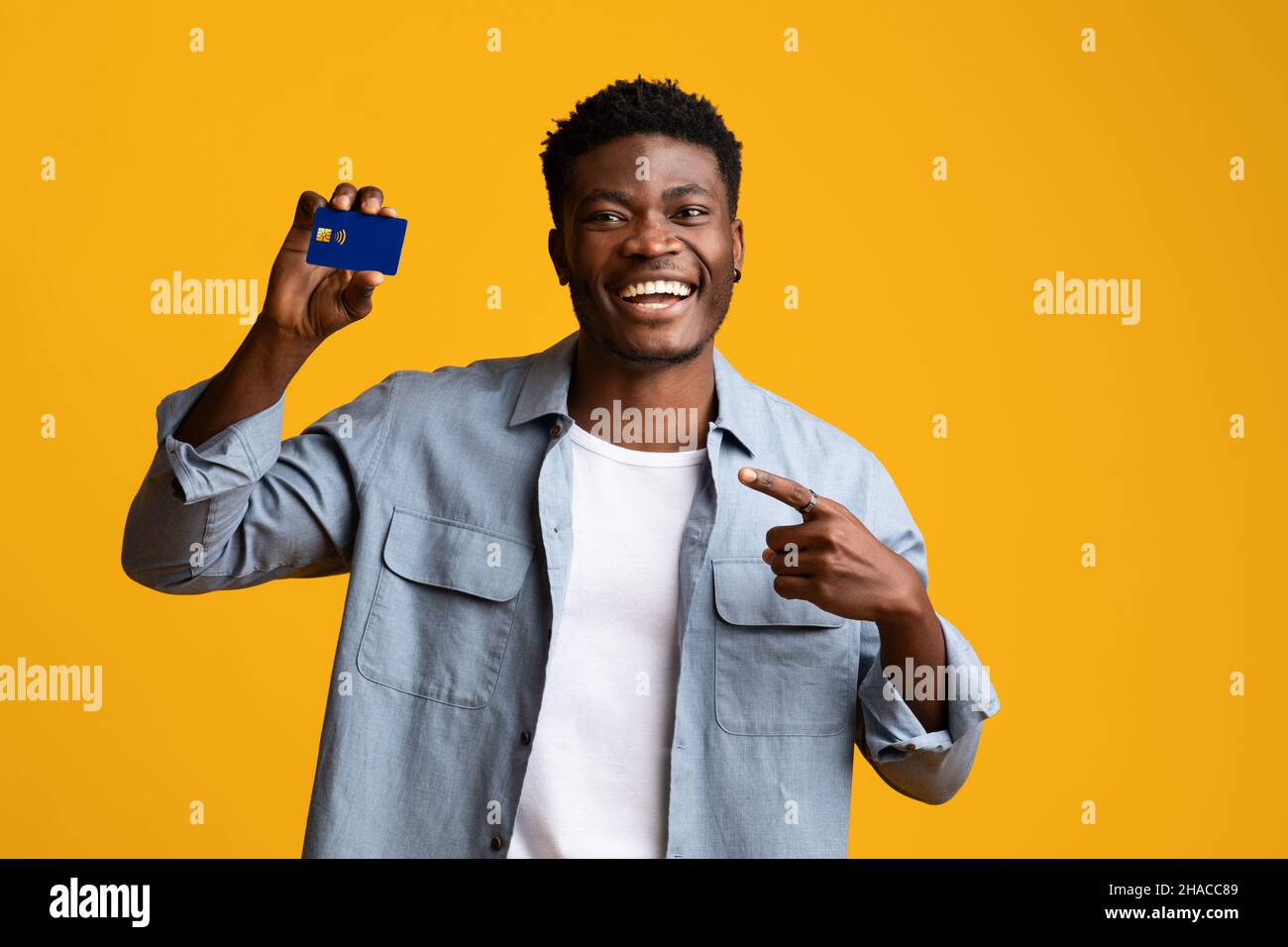 Happy black guy showing credit card on yellow Stock Photo - Alamy