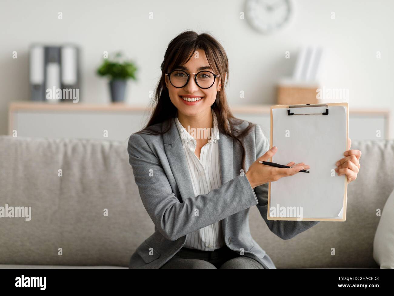 Cheerful arab female psychologist showing clipboard, having session ...