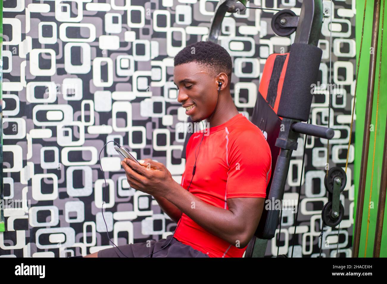 happy guy using his phone in gym during break Stock Photo - Alamy