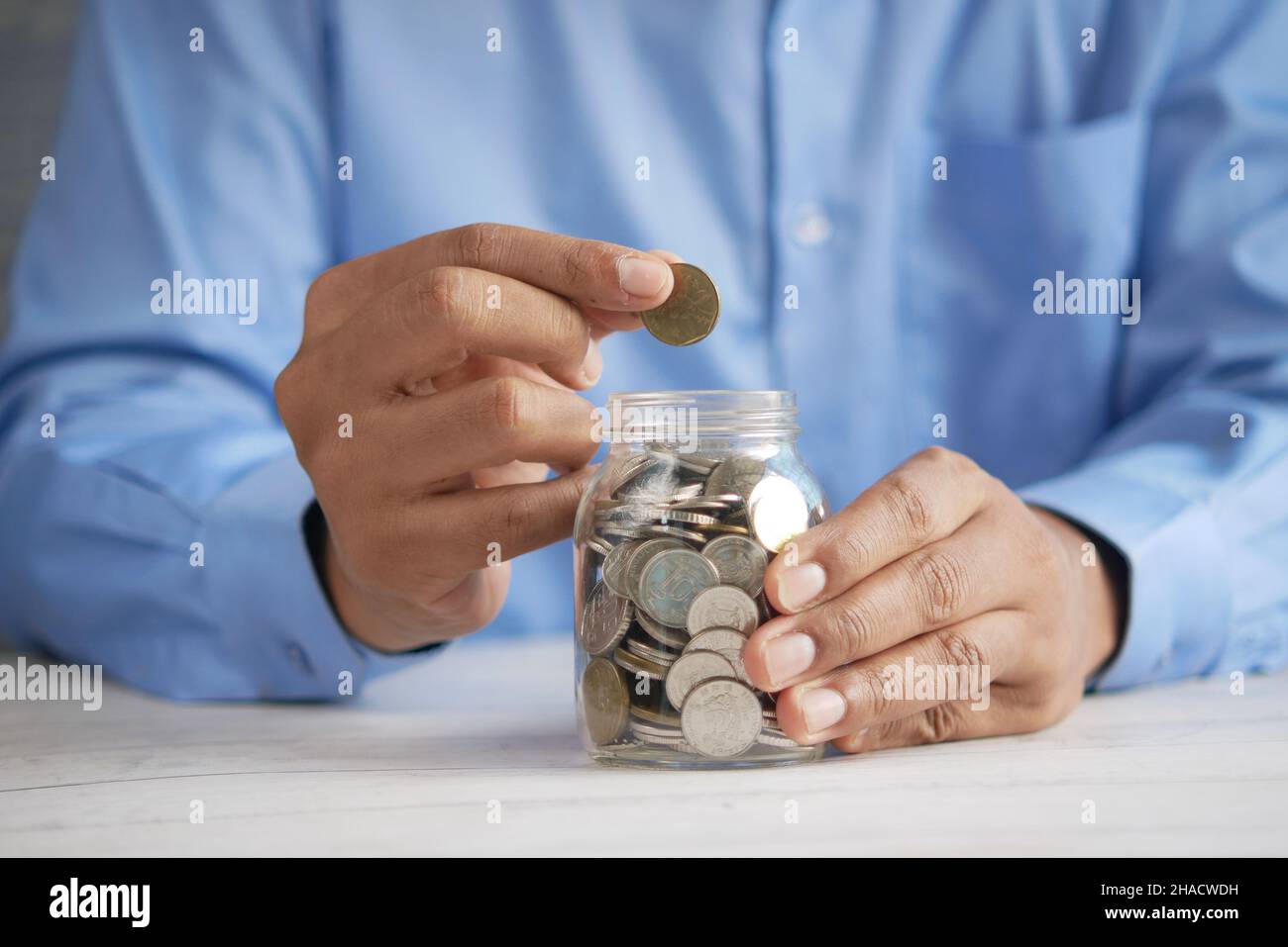 young man saving coins in a jar white sited Stock Photo - Alamy