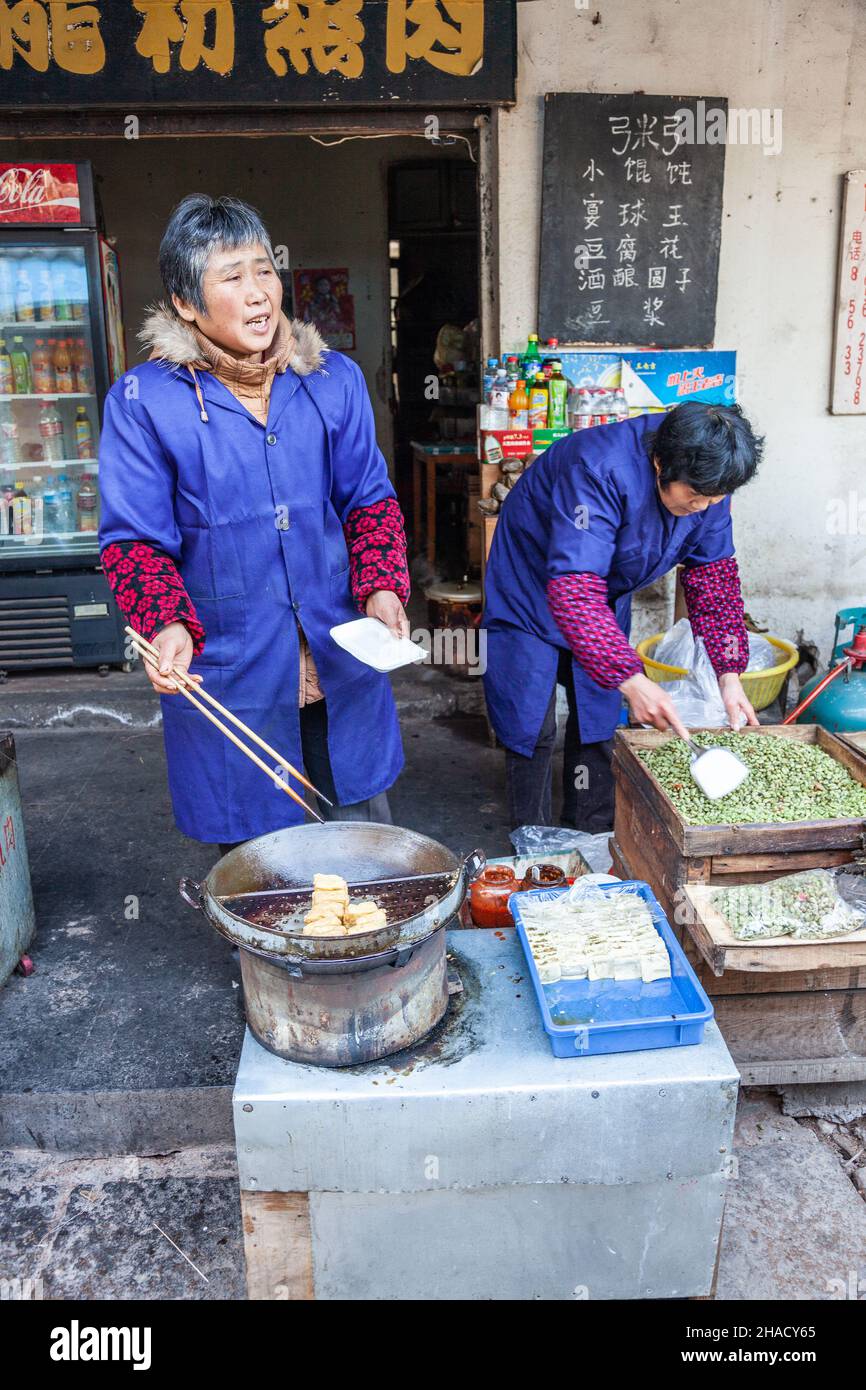 Lady cooking and offering snacks on the street. Xitang, China Stock ...