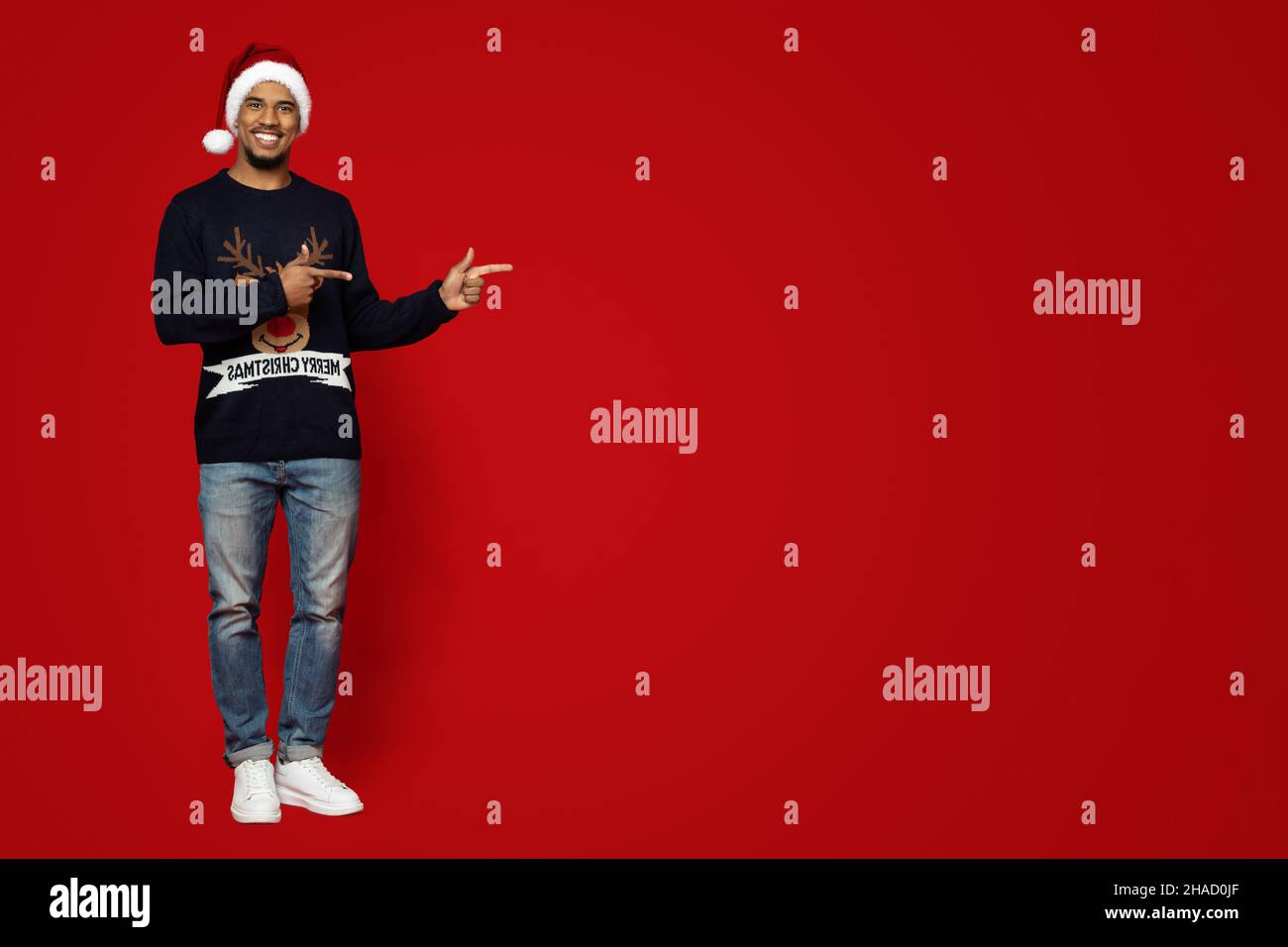 African american man in Santa hat pointing at copy space Stock Photo ...