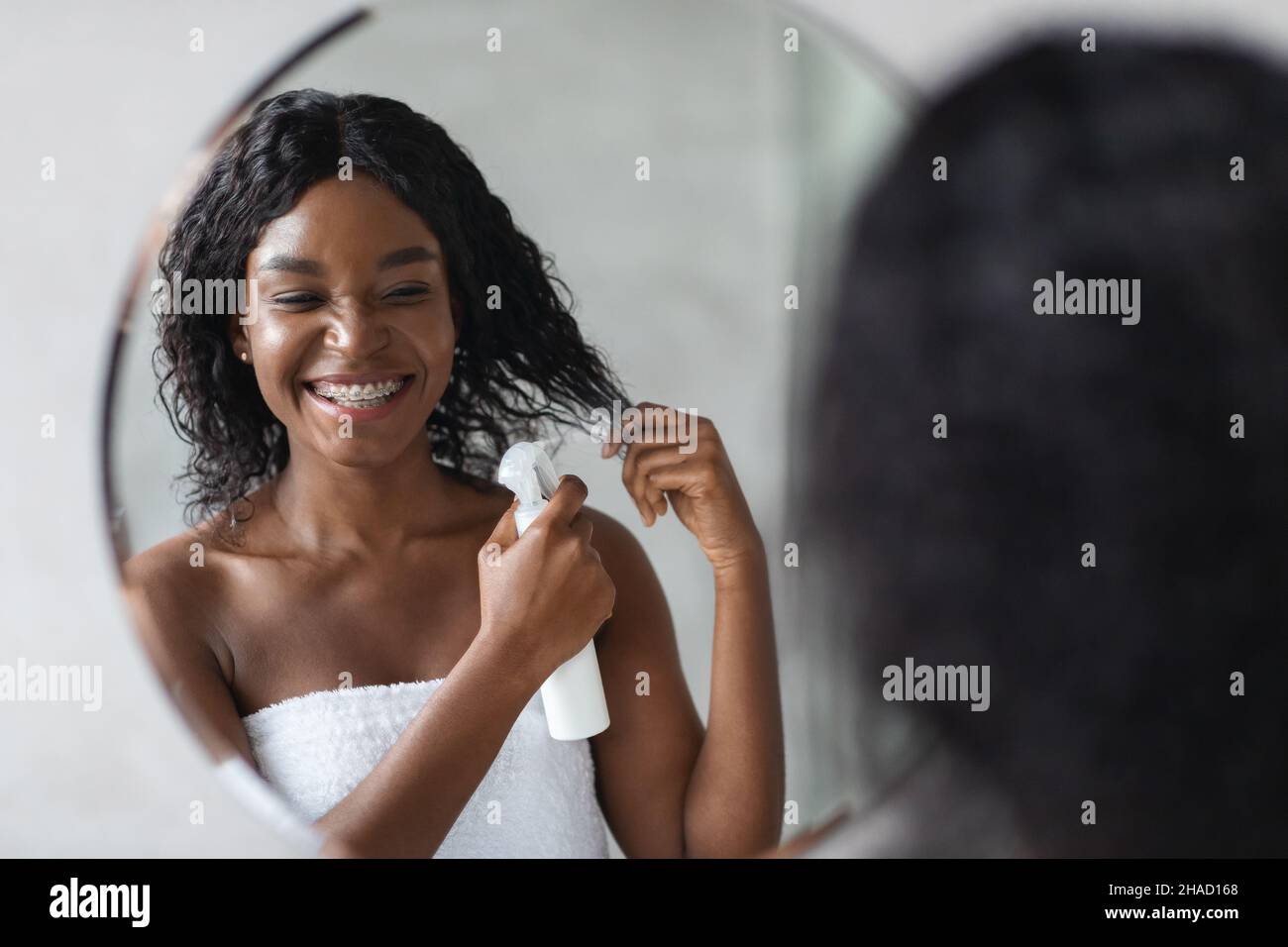 Happy young black woman using hair spray Stock Photo - Alamy