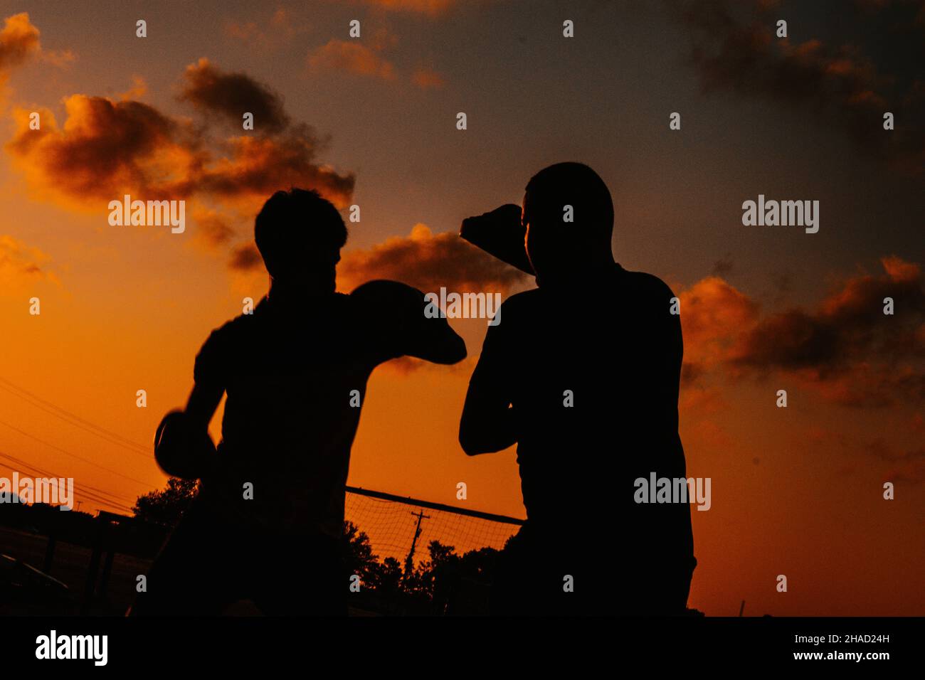A silhouette of two boxers in a training fight outside under a cloudy ...