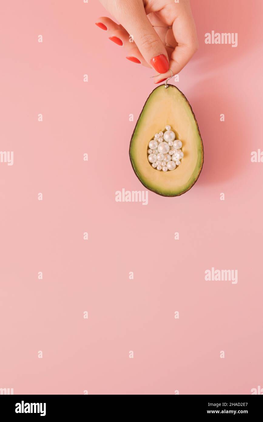 A woman's hand holding an avocado with pearls rather the seeds on a ...