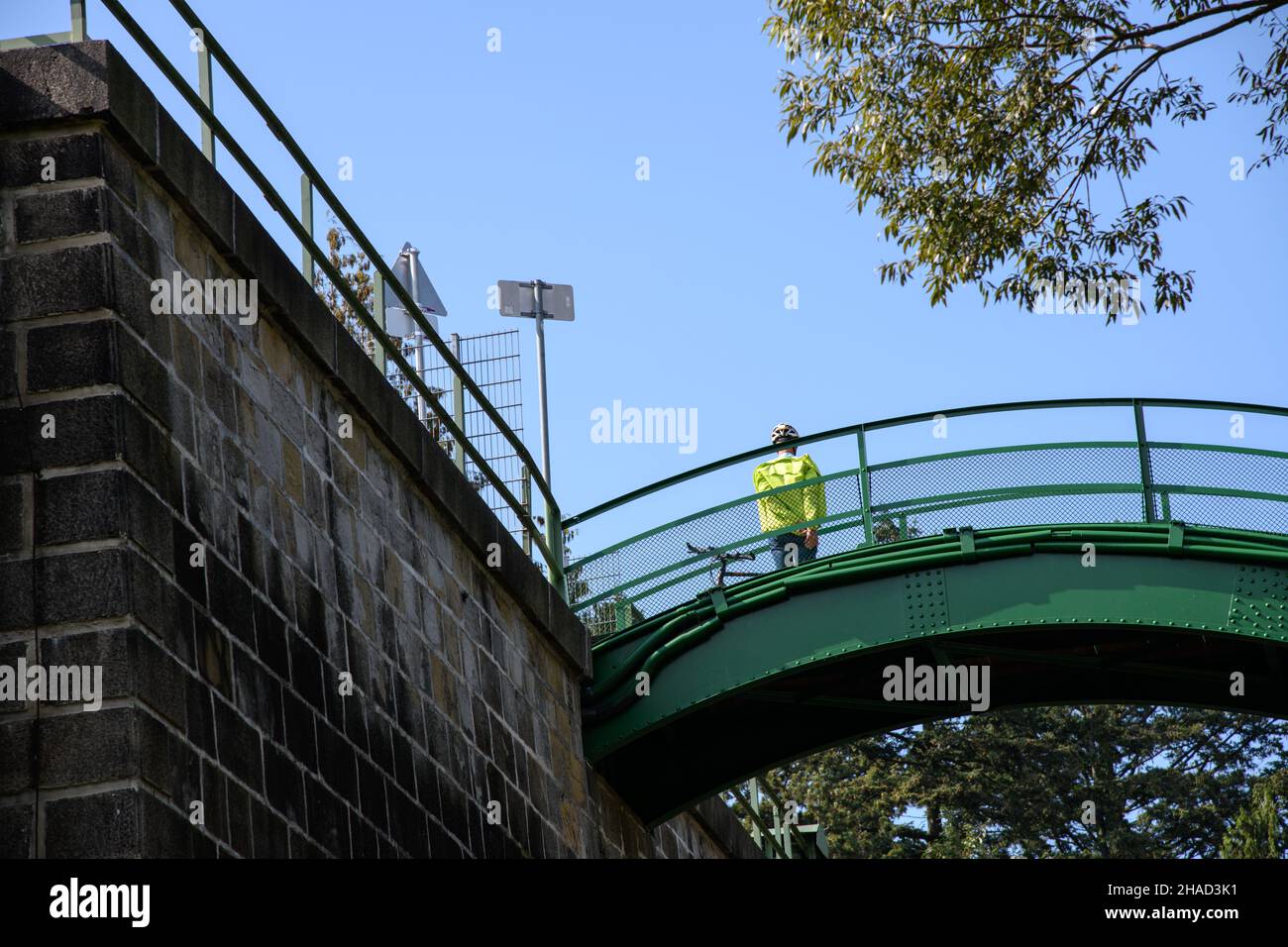 A lone cyclist stands on a steel arch bridge and takes a break Stock ...