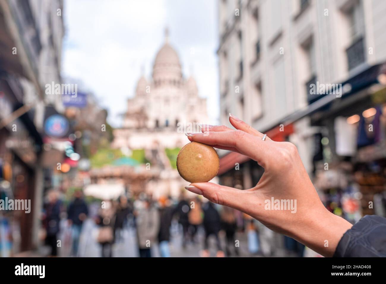Hand holding a french macaroon cookie, Macaron, on the street of Paris ...