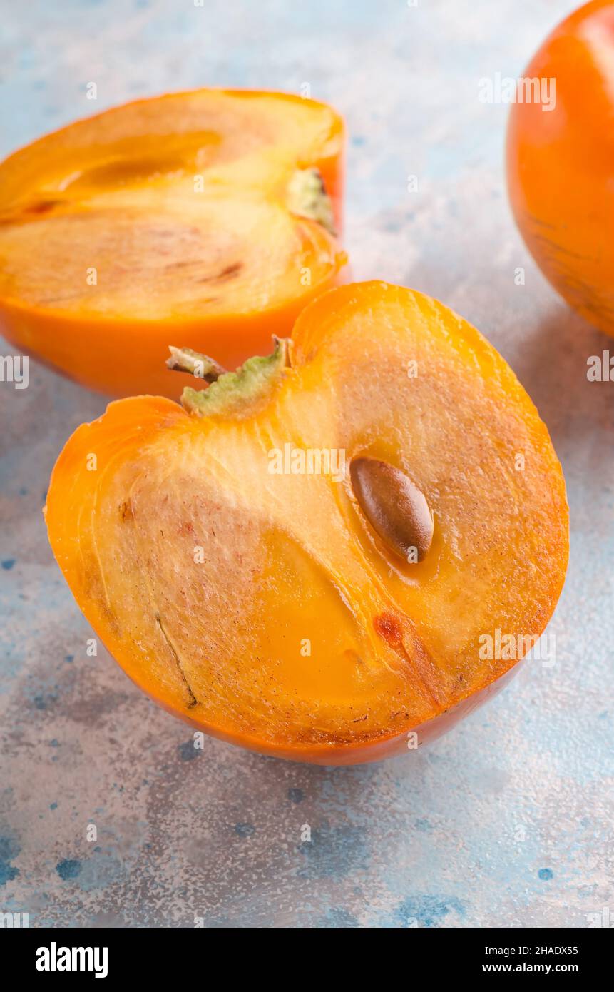 Cut persimmon with a bone on the table on a gray-blue background close ...