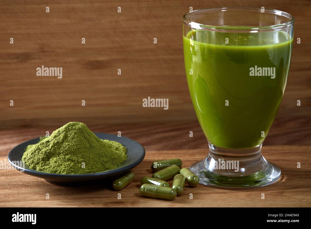 Capsules filled with Moringa powder and moringa juice on wooden ...