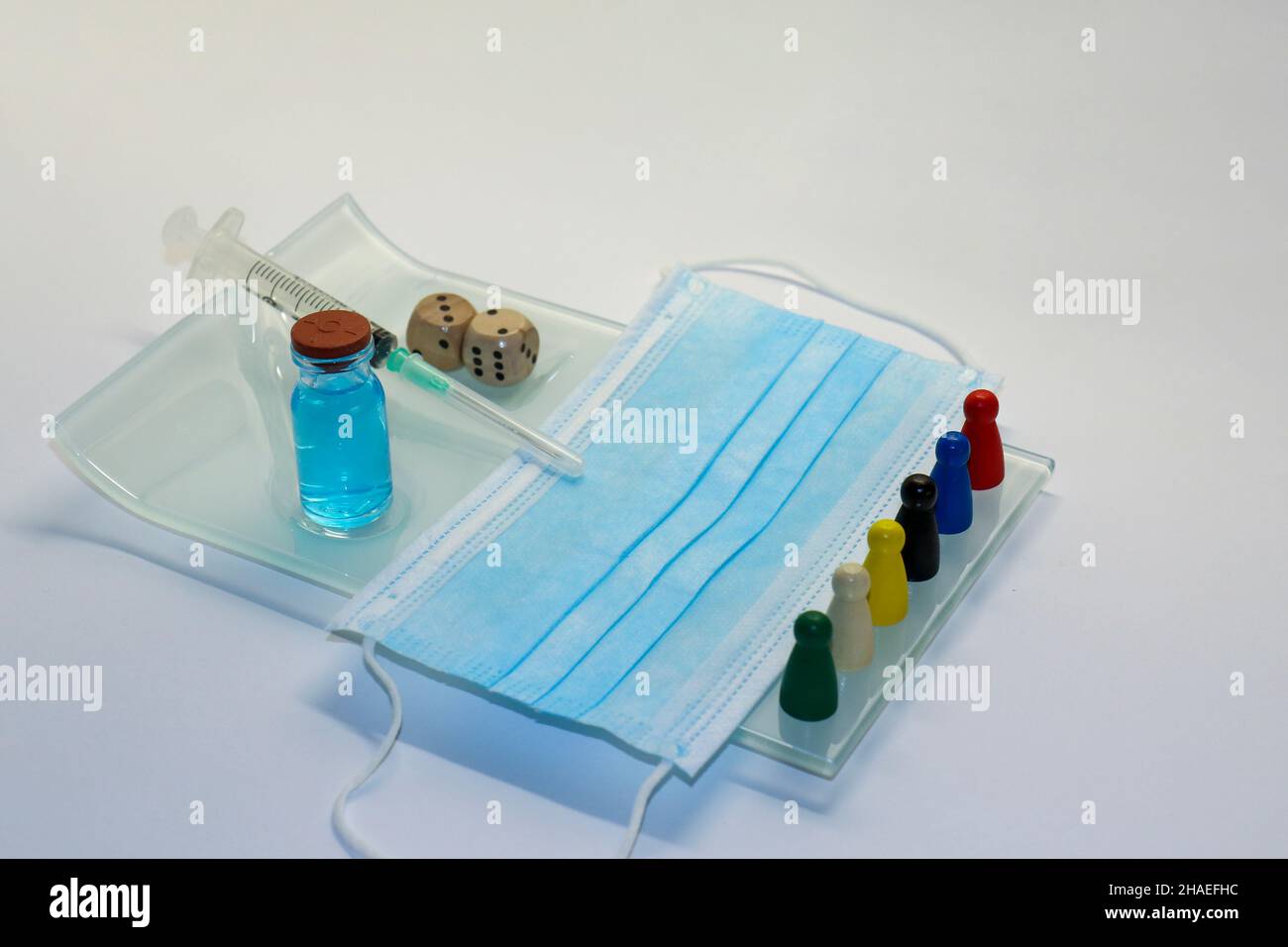 Medical syringe, vaccine vial and surgical face mask on glass tray ...
