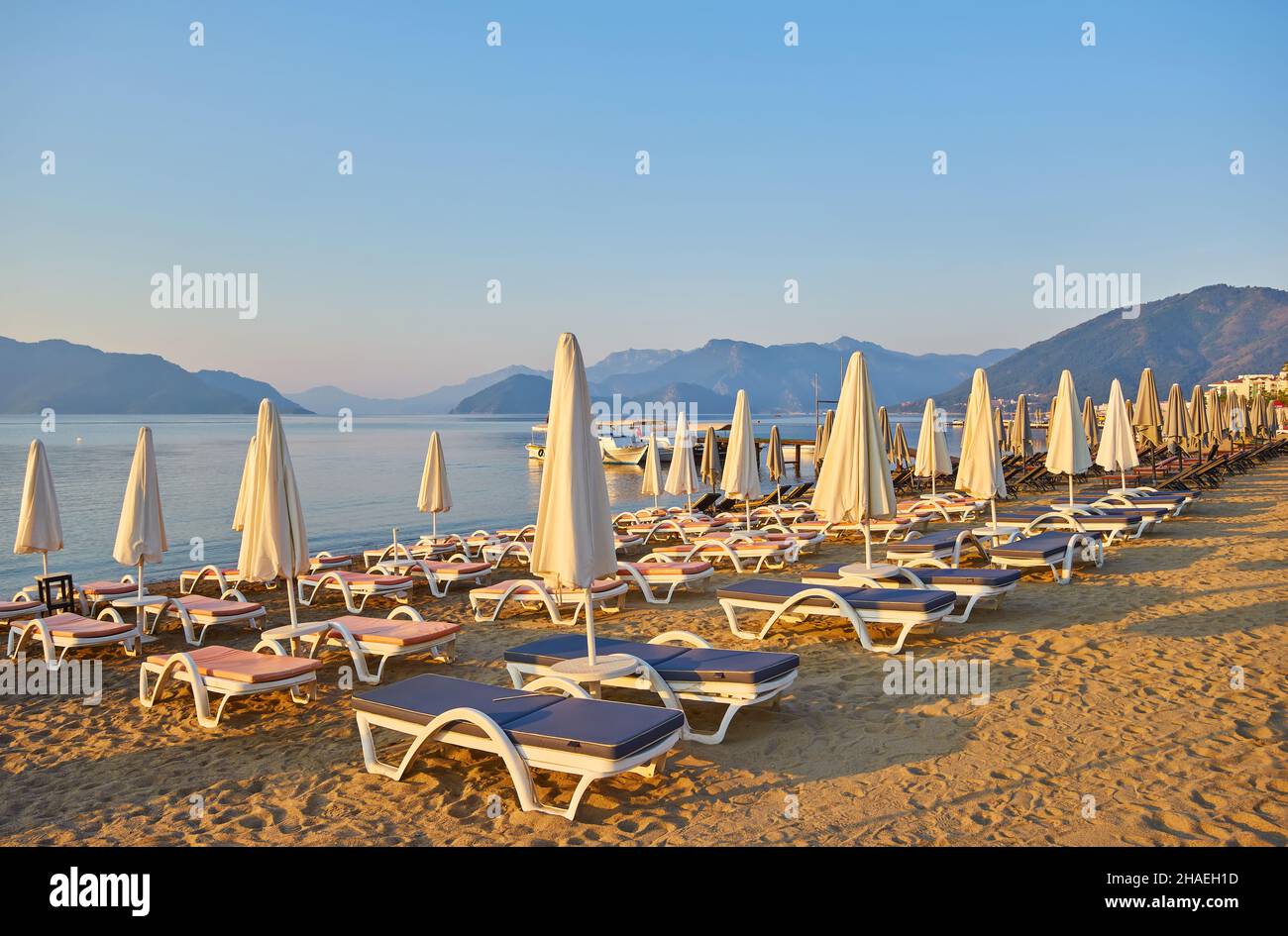 sandy beach without people and with sun loungers, umbrellas, palm trees ...