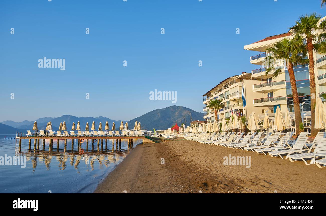 sandy beach without people and with sun loungers, umbrellas, palm trees ...