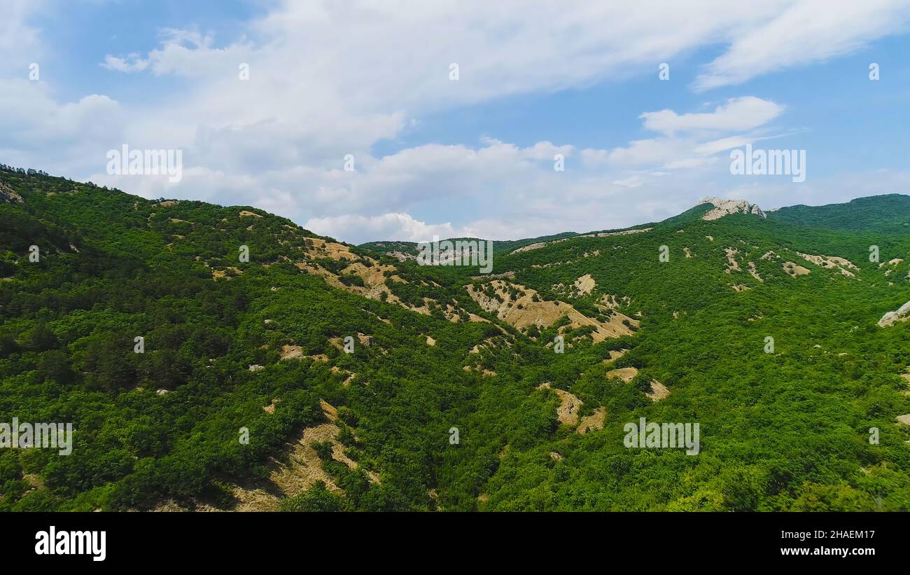 Top view of steep rocky slopes at top of green mountain on background ...