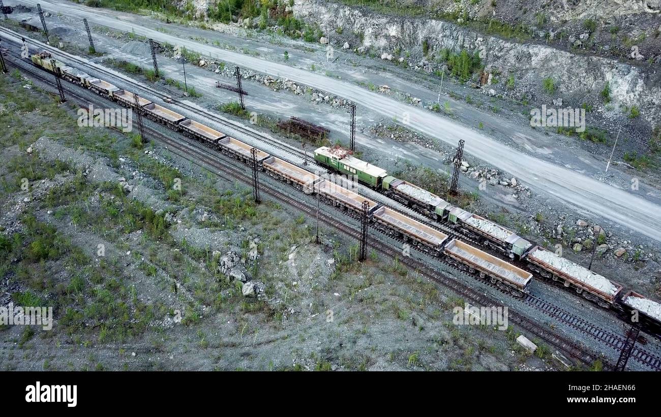 Diesel locomotive is pushing dump-car filled with rubble stone in the ...