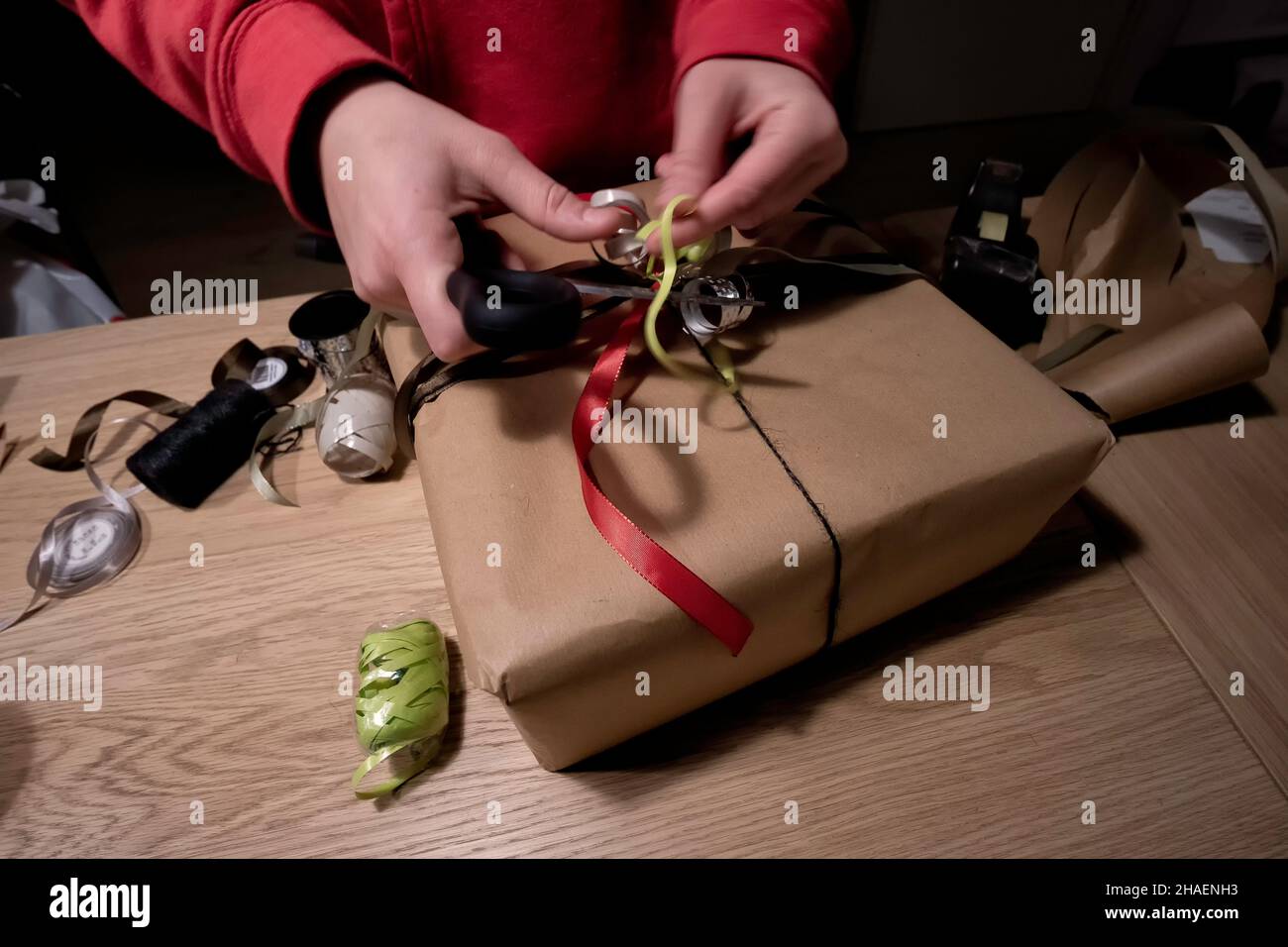A person wrapping a present in giftpaper and tying a ribbon around the ...