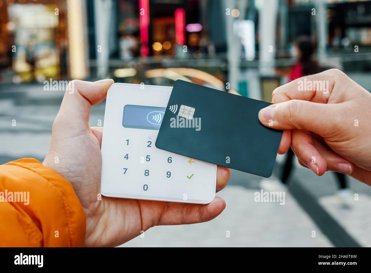 Crop anonymous female customer with credit card making contactless ...