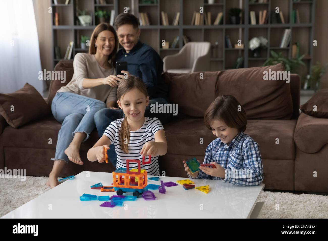 Happy small kids playing toys while parents using cellphone Stock Photo ...