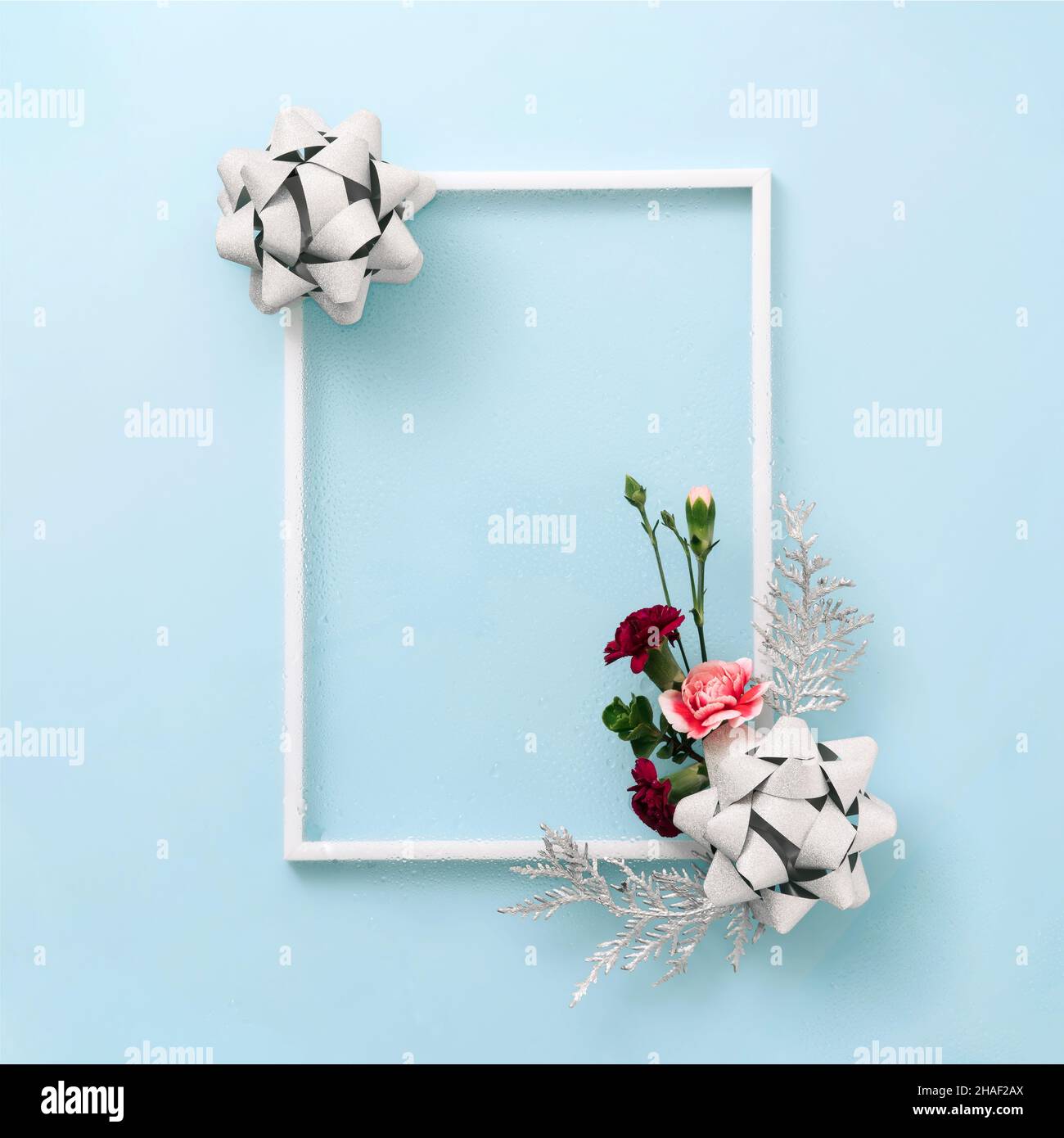 Creative festive layout with flowers and silver sprigs, with bows and a ...